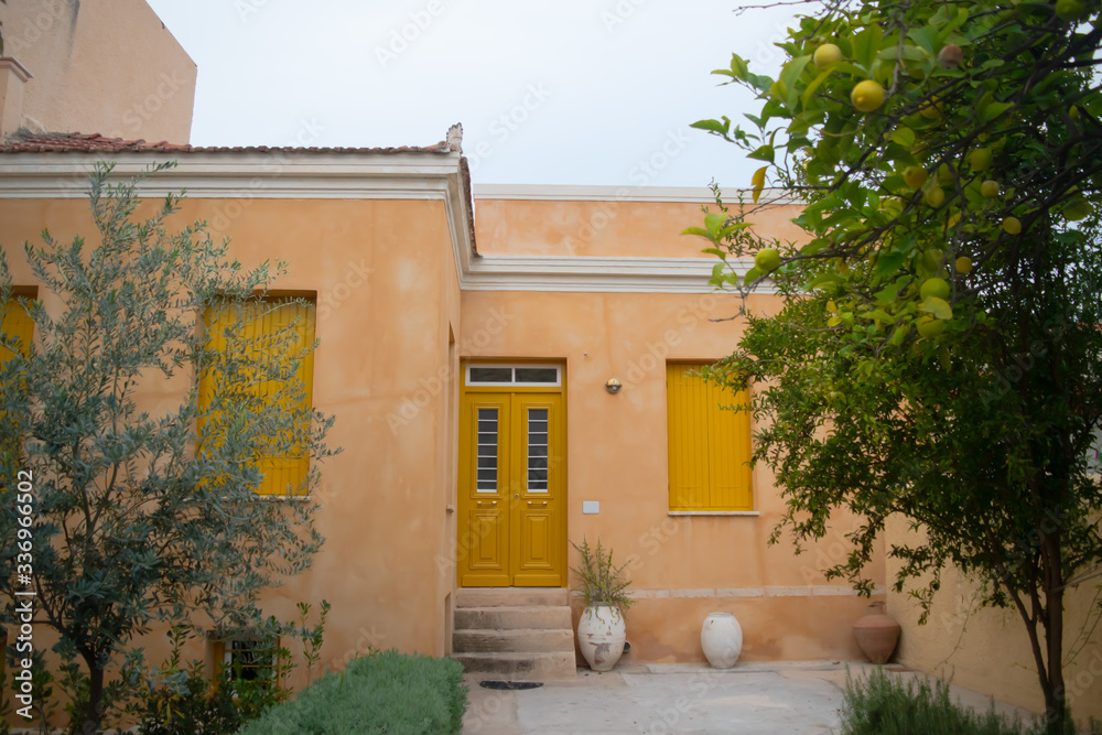 Salmon colored house facade and yellow doors and windows with an olive ...