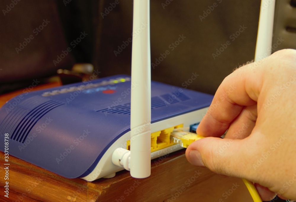 connecting the router to the network cable by plugging in the cable to ...