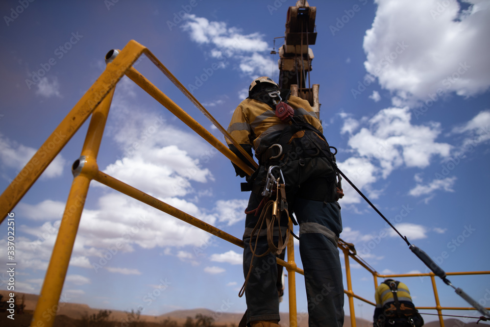Safe workplace rigger wearing working at heights harness clipping an ...