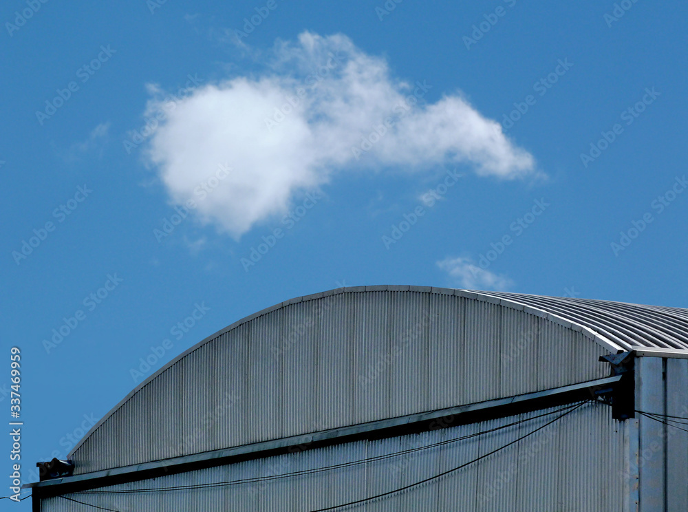 arched corrugated aluminum hangar building top detail. blue sky. white ...