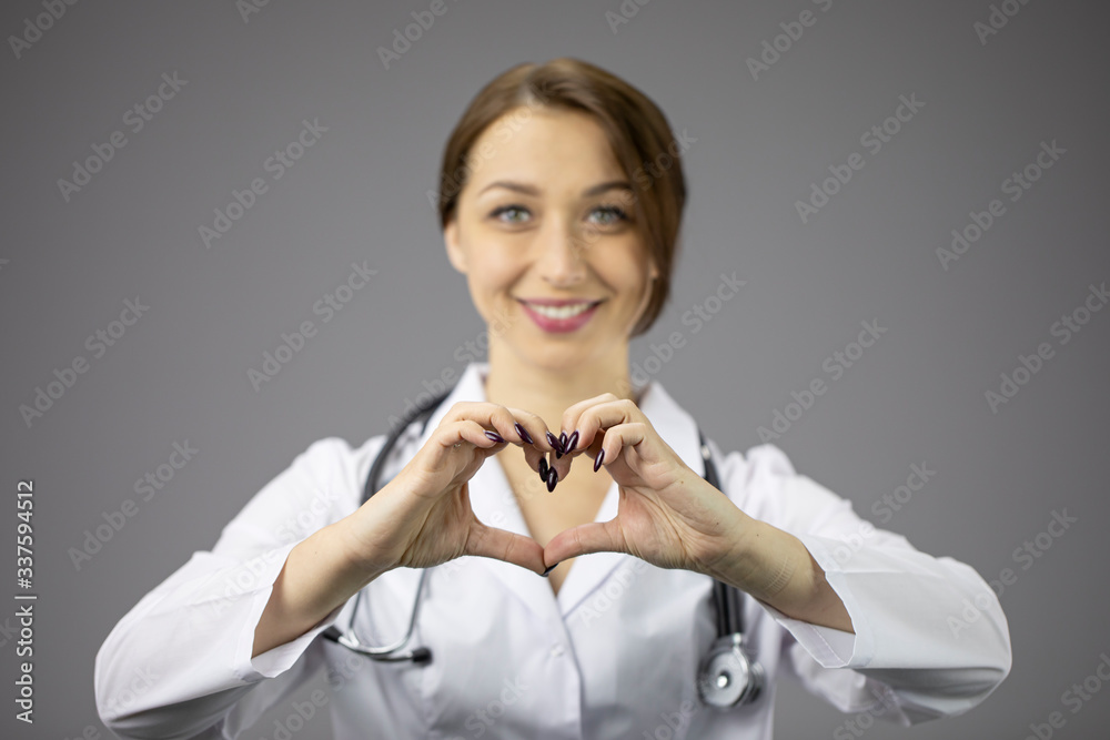 Sexy female doctor with a stethoscope in a white coat on a gray ...