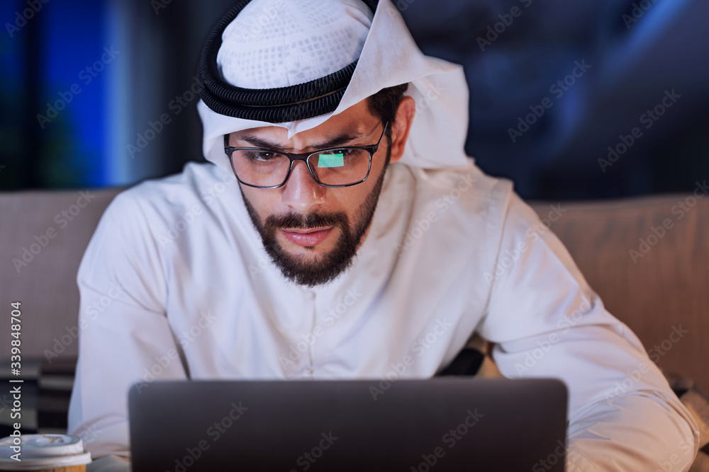 Arab man working from home sitting on sofa late at night time ...