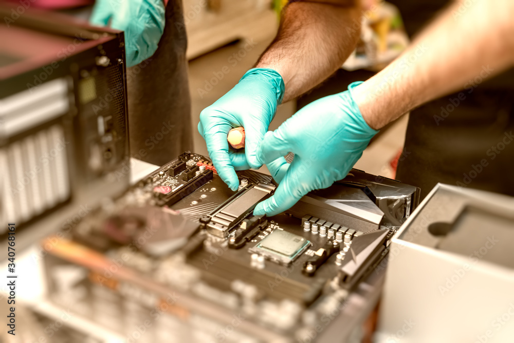Personal computer technicians mounting ssd drive on the motherboard ...