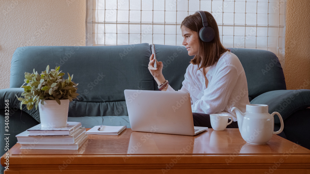 Girl telecommuting and making a video call from home in the living room ...