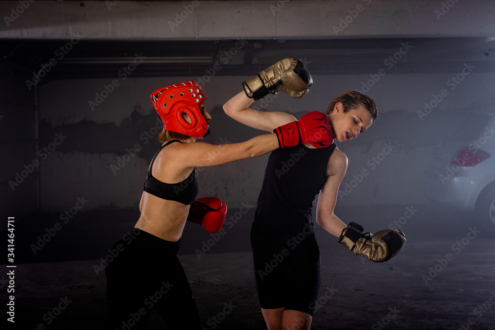 Two professional female boxers punching each other in aggressive garage ...