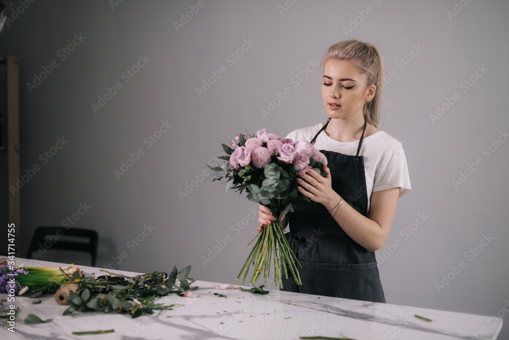 Professional young woman florist wearing apron making floral ...