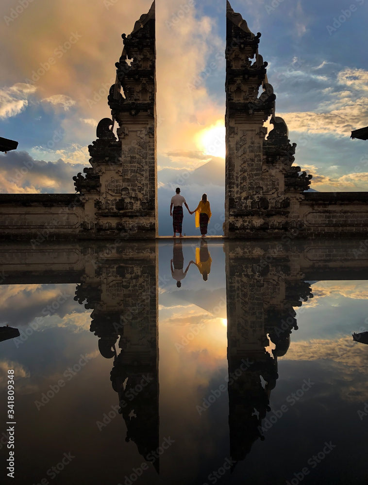 Happy young couple staying in temple gates of heaven and holding hands ...