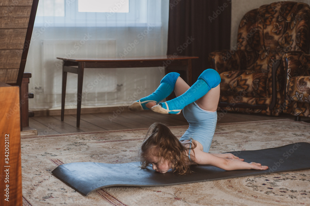 Little cute girl is practicing gymnastics at home. Online training ...