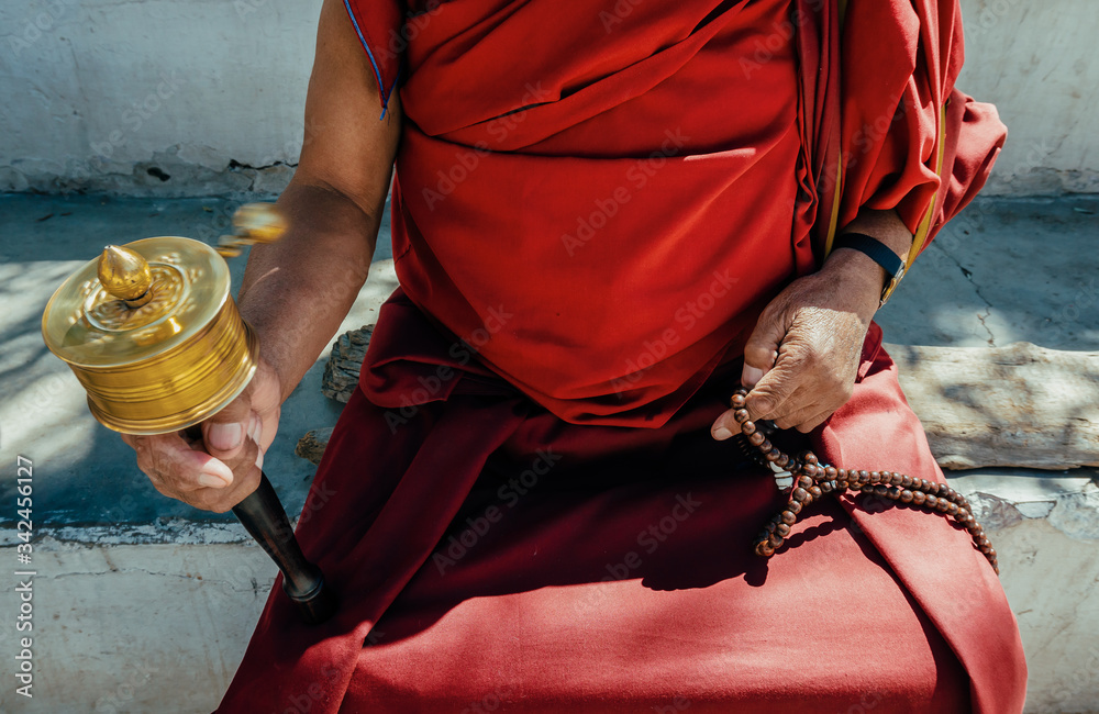 Hands of a Tibetan Buddhist monk with a spinning Tibetan prayer wheel ...