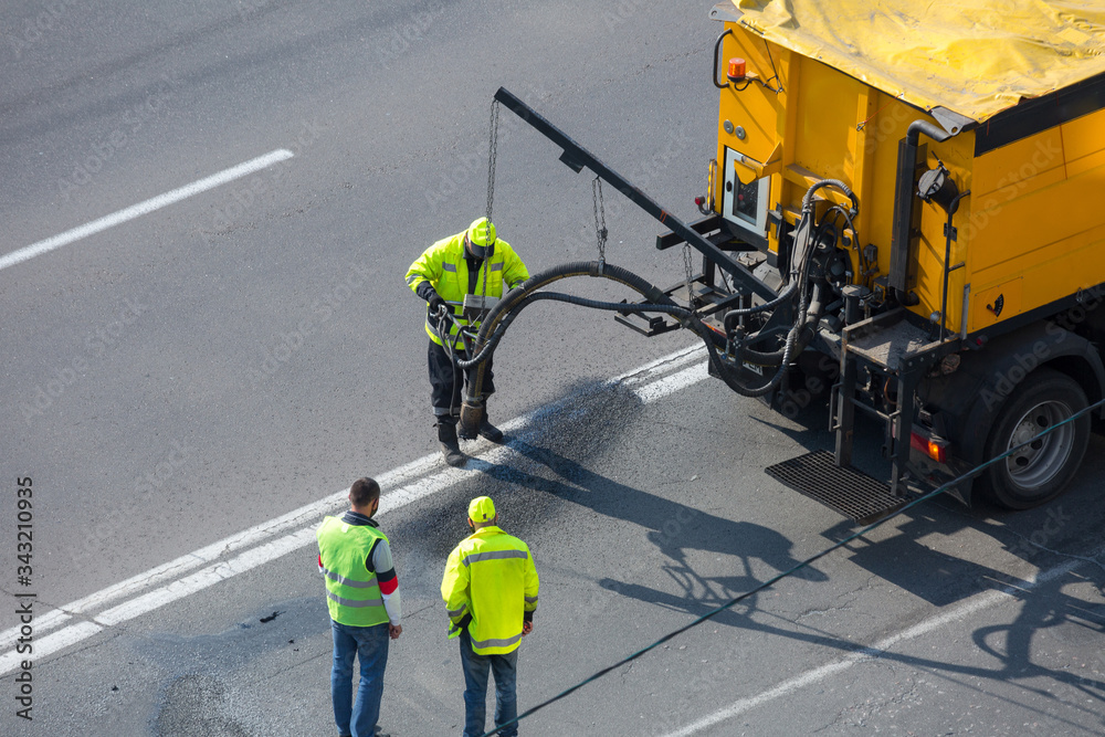 Road surface restoration work. The worker performs on road patcher work ...