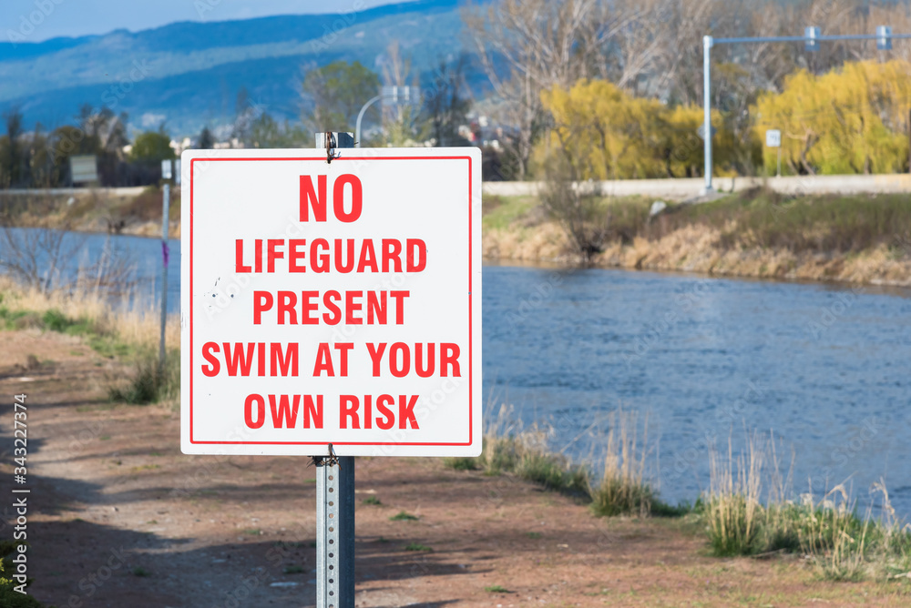 No lifeguard swim at own risk warning sign with river channel in ...