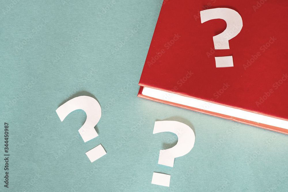 three question marks cut out of paper, one of them on the red book ...