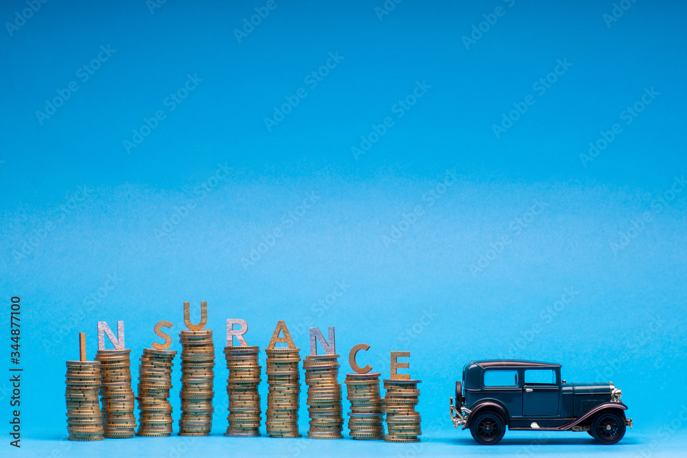 Dark blue car figurine next to some tall columns of coins each with a ...