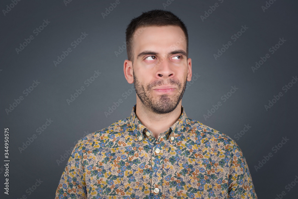 Gloomy, wondering young man face looking up lips together, being upset ...