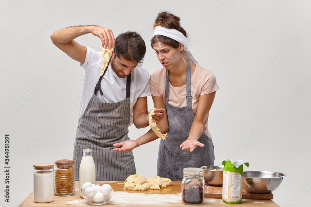 Busy couple knead dough together, surrounded with tools for cooking ...