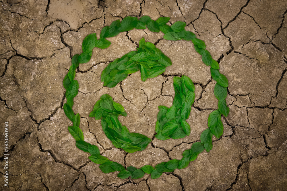 Ecology sign laid out by green leaves on cracked earth. Arrows from the ...