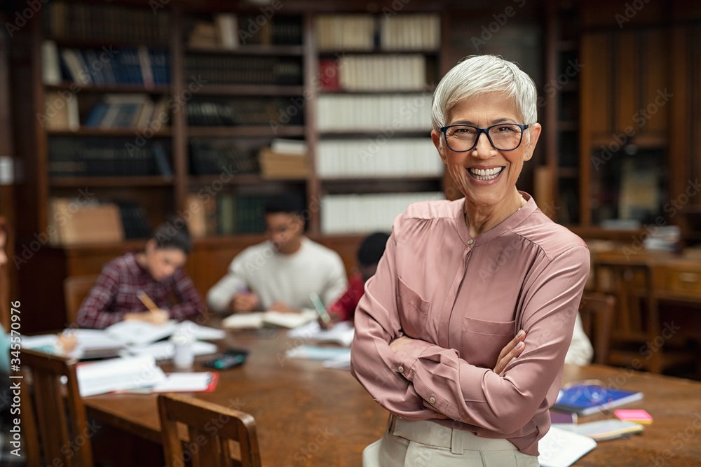 Smiling university professor in library Stock Photo | Adobe Stock
