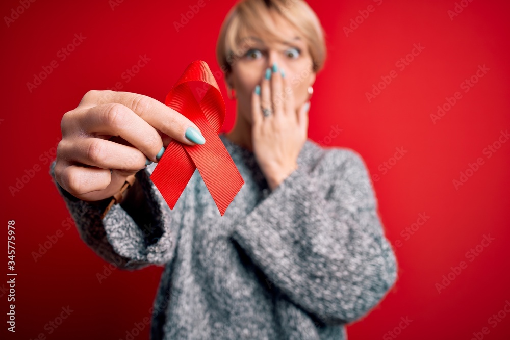 Young blonde woman with short hair holding hiv and aids awareness red ...