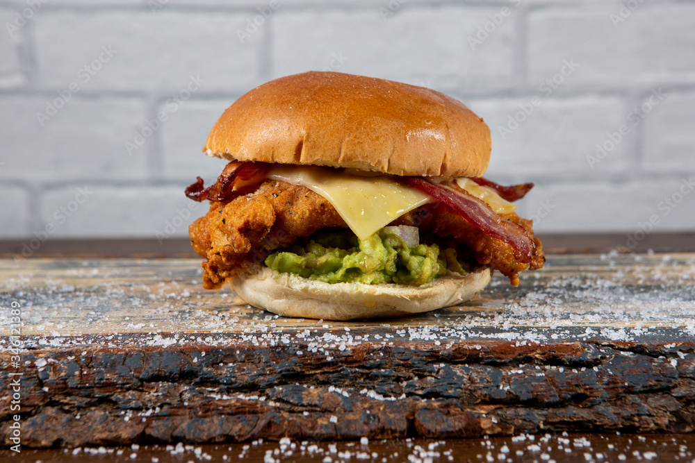 Chicken and bacon burger and fries on a slate plate and a white brick ...