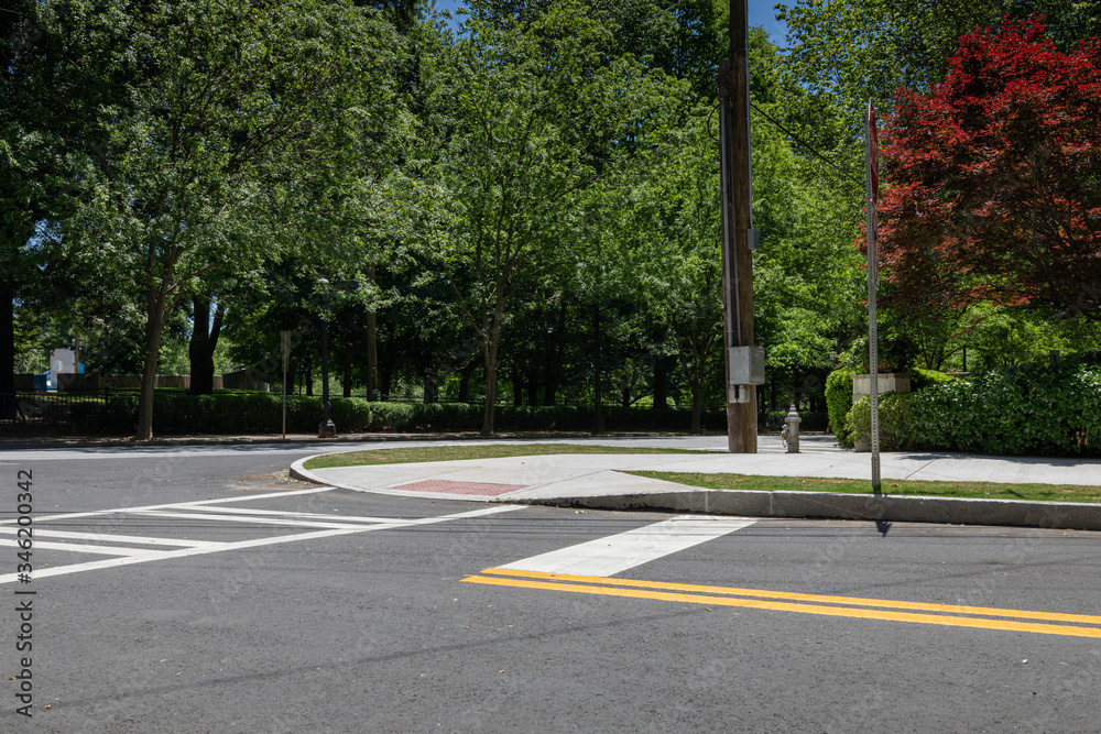 Intersection of two streets in an urban city landscape, park with trees ...