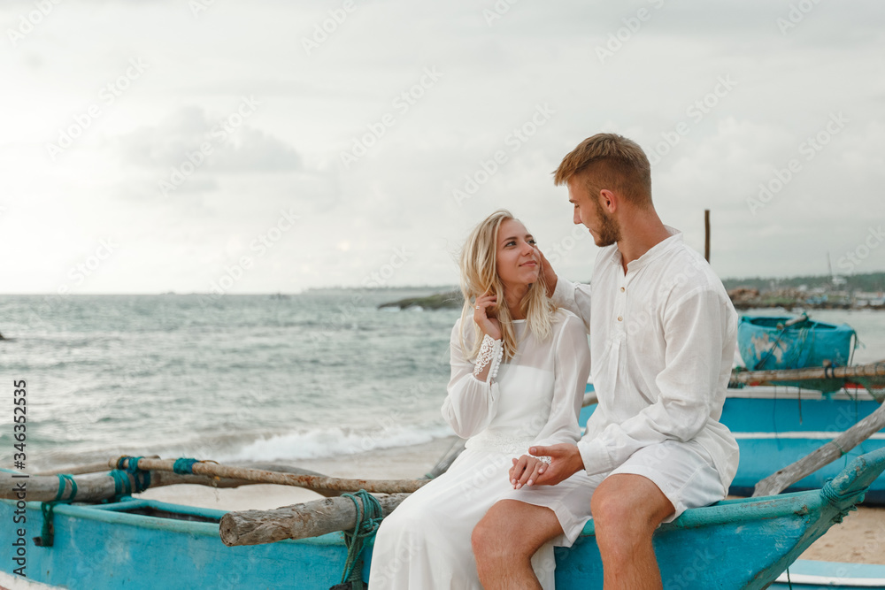 Happy Romantic honeymoon couple on the beach sitting on traditional ...