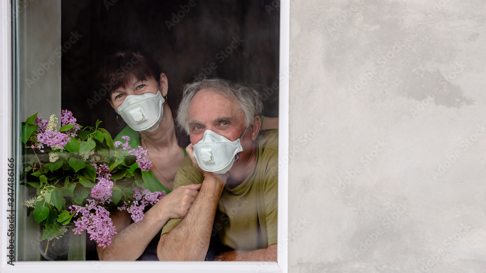 Banner. Older couple hug. loving woman and man look out window in masks ...