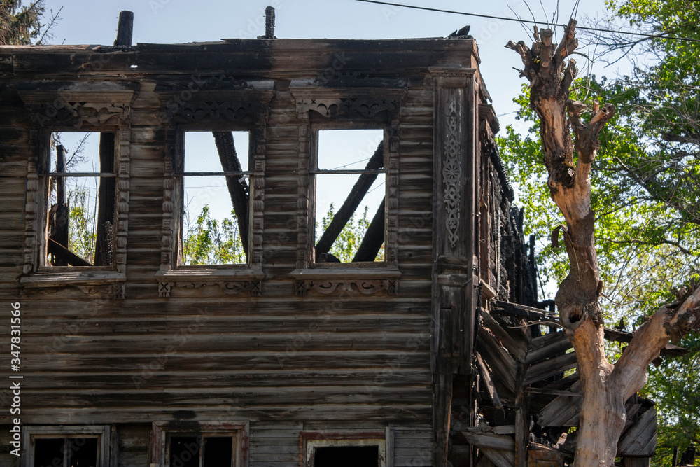 The ruins of a wooden house after a fire. Burnt logs of a two-story ...
