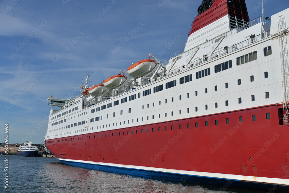 arge white-red ship with small boats on board enters the port Stock ...