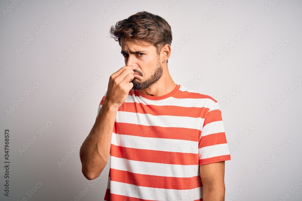 Young handsome man with beard wearing striped t-shirt standing over ...
