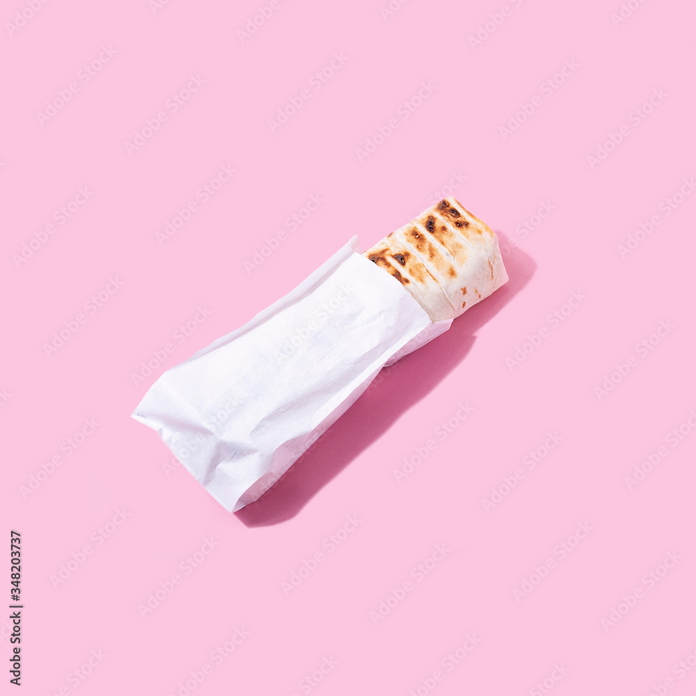 Gyro pita or shawarma with paper wrap on pastel pink background in pop ...