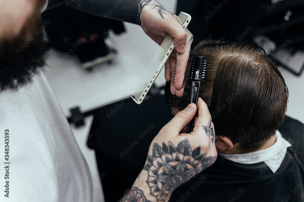Professional tattooed barber using cutthroat razor cutting hair ...
