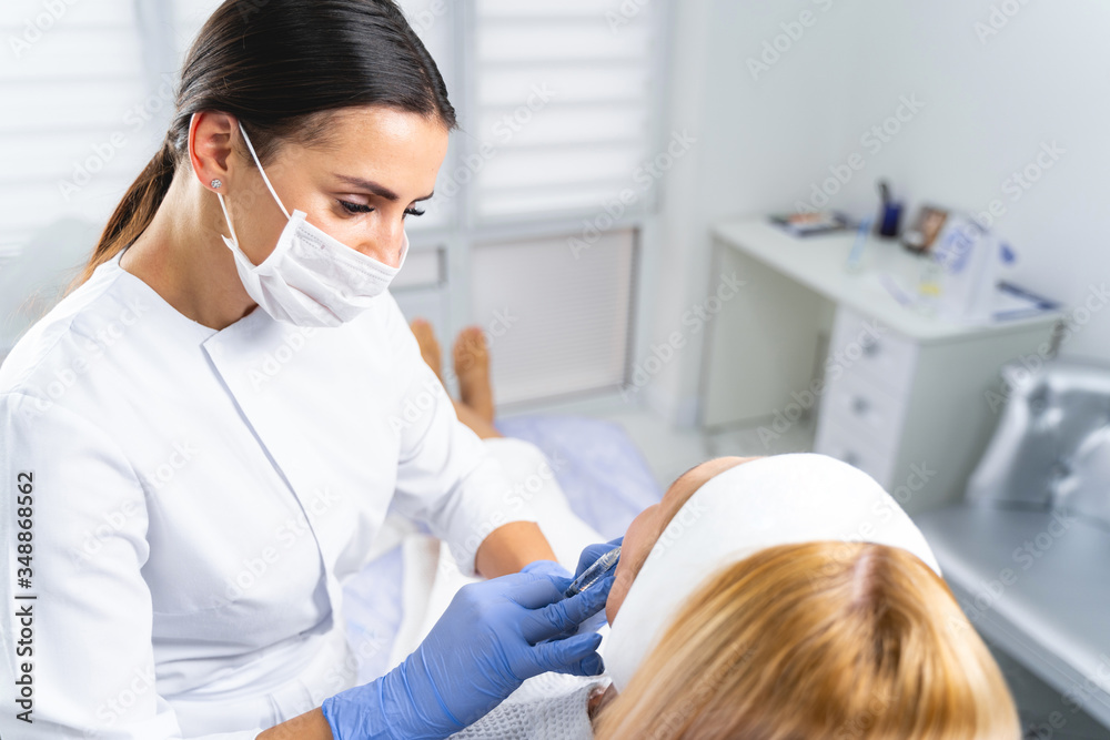 Foto de Stock Dermatologist in a face mask treating a woman | Adobe Stock