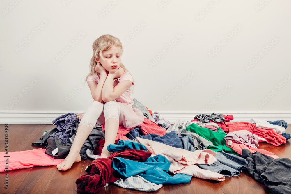 Mommy little helper. Bored Caucasian girl sorting clothes. Tired funny ...