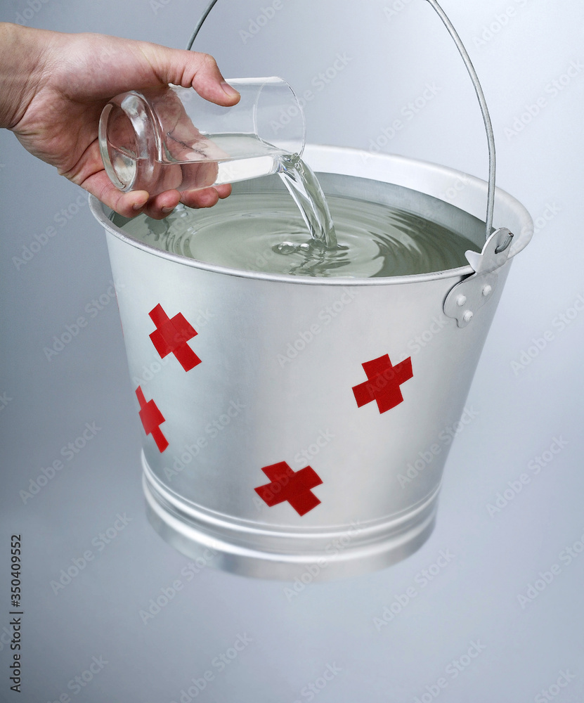 Hand pouring water from a glass into a pail の Stock フォト | Adobe Stock