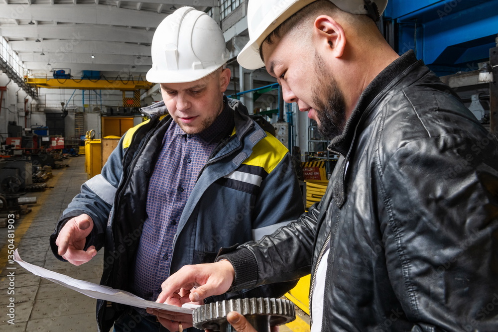 Two young engineers at a modern factory. The photo illustrates new ...