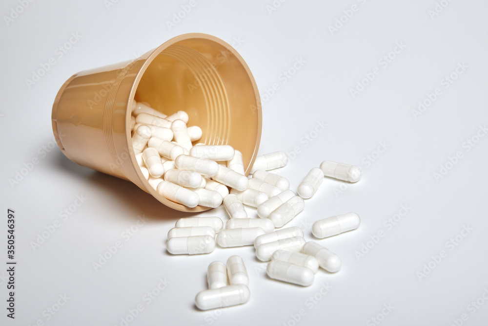 Plastic cup spilling a lot of pills. Concept of chronic disease and ...
