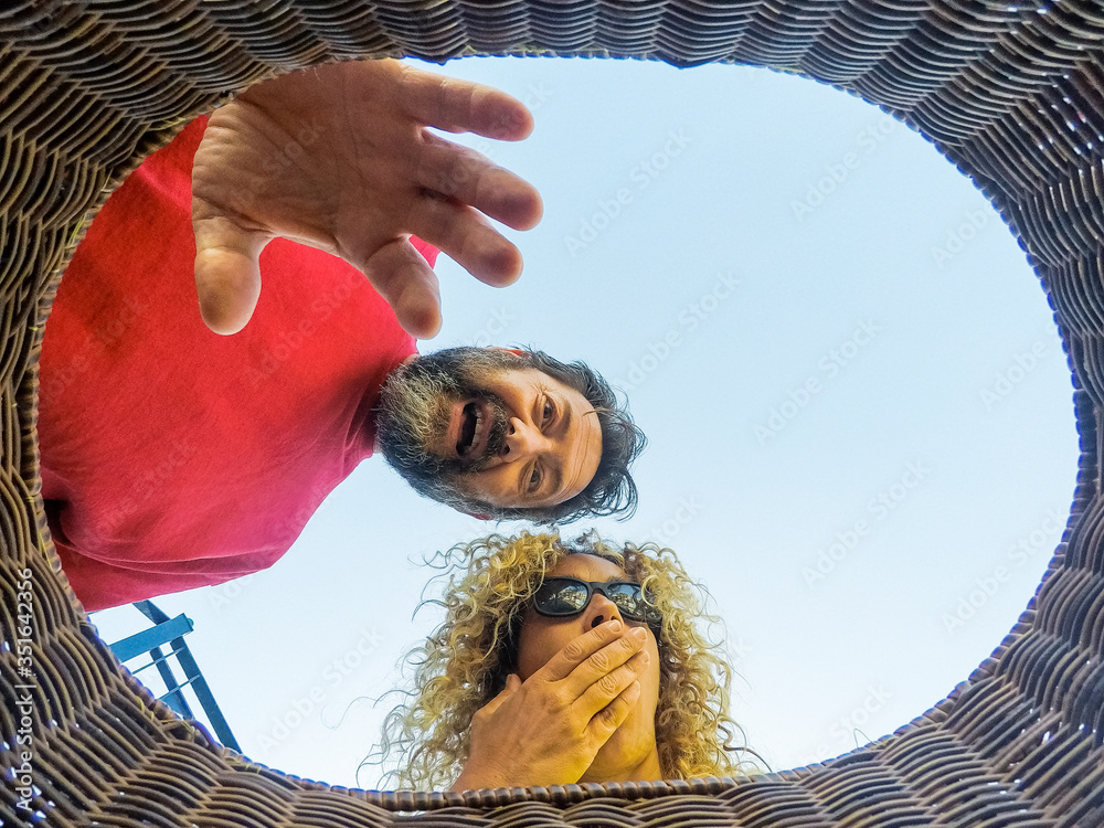 Adult caucasian couple look inside a bucket and do surprised expression ...