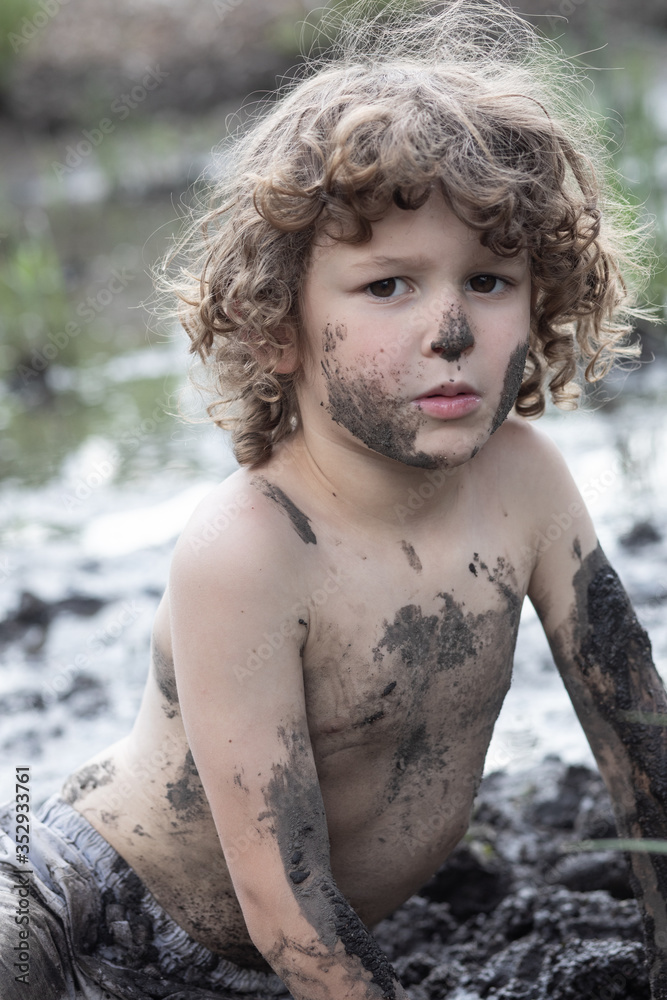 Foto stock di A little boy is playing in the mud. He is covered in dirt ...