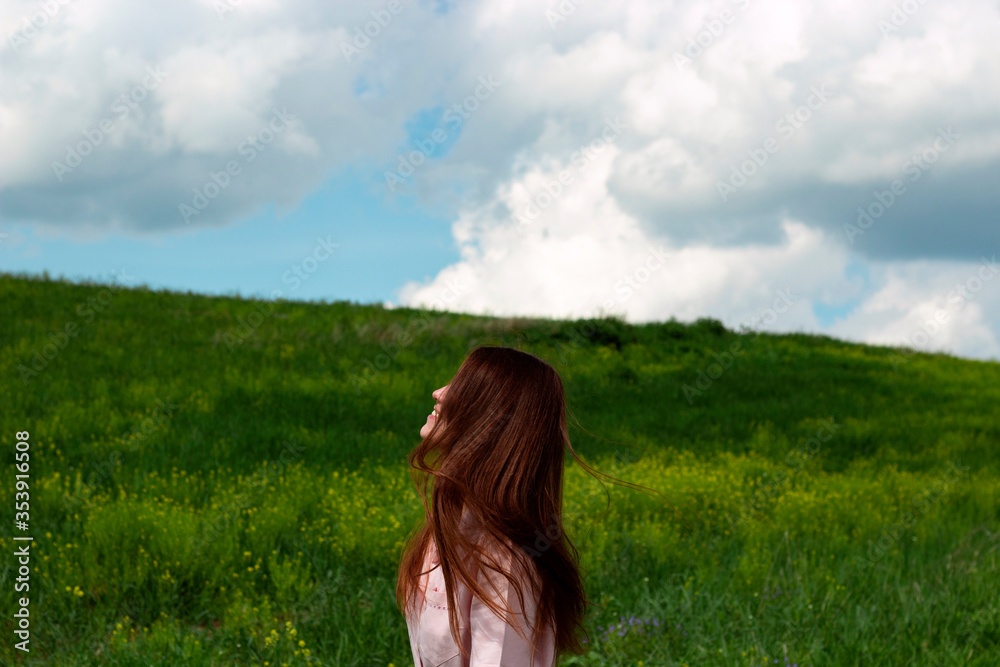 Dreaming girl on a green margins. The girl stands with her back to the ...