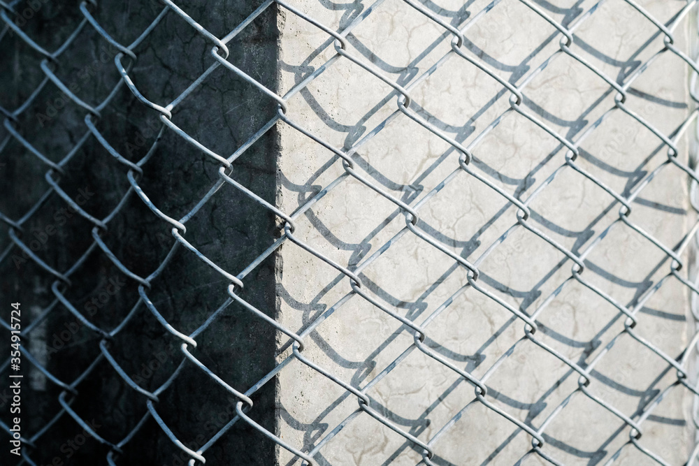Corner of gray painted squared pillar covered with metal wire mesh ...