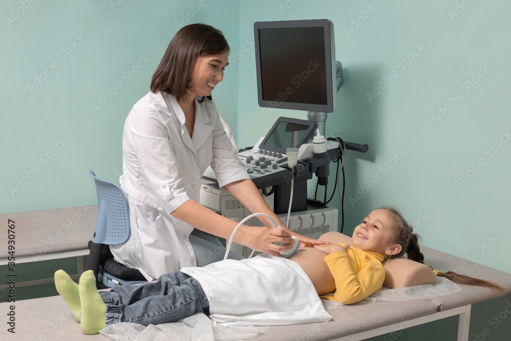 Doctor making abdominal ultrasound for child girl using scanner machine ...