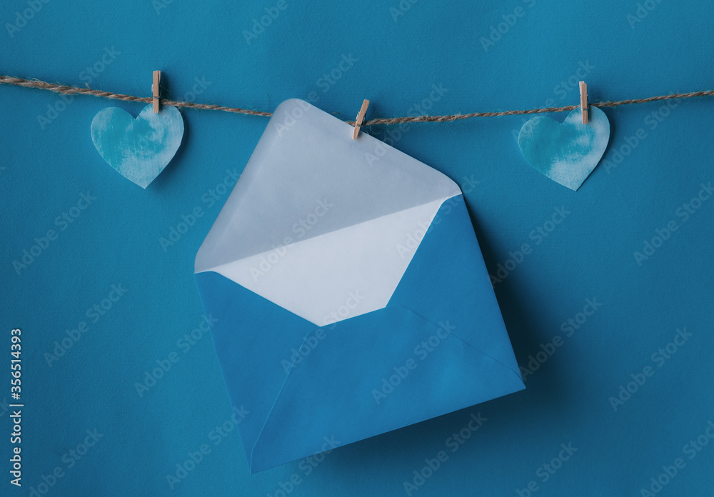 One opened blue envelope hanging on rope isolated blue background with ...