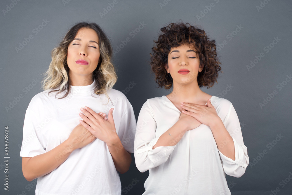 Faithful woman closes eyes and keeps hands on chest near heart, shows ...