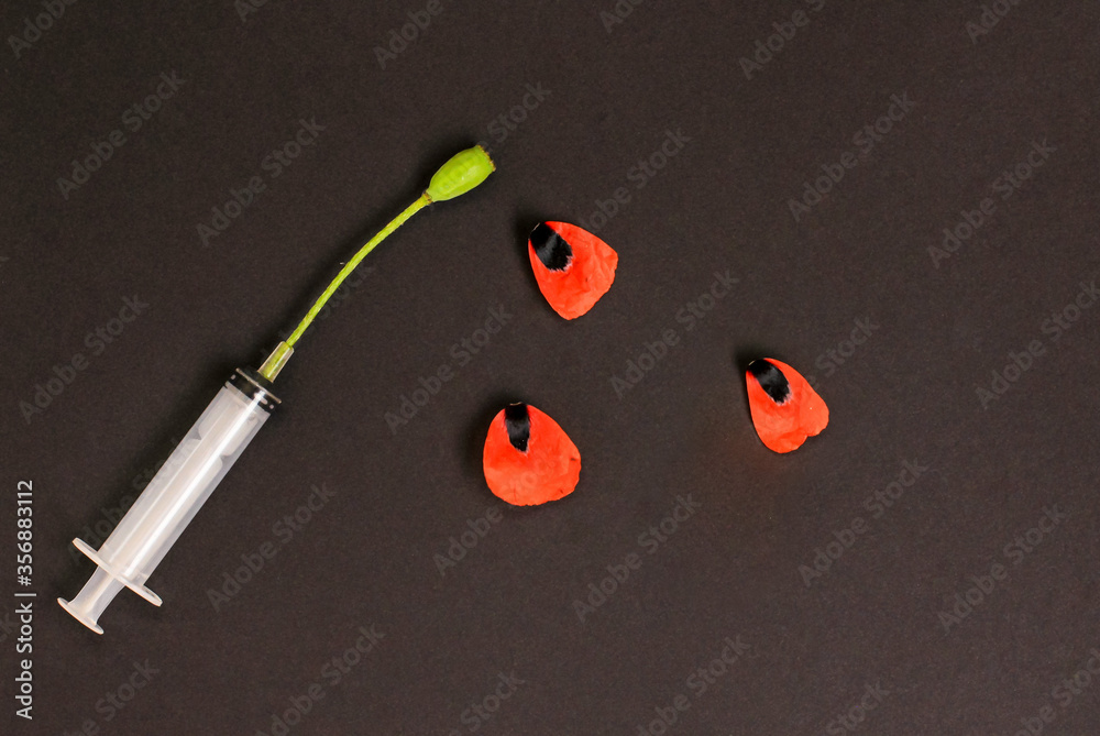 Medical syringe with a poppy flower that has lost its petals (like ...