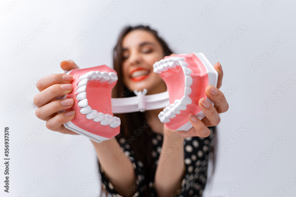 Funny girl toing with dental jaw on white background. Opened plastic ...