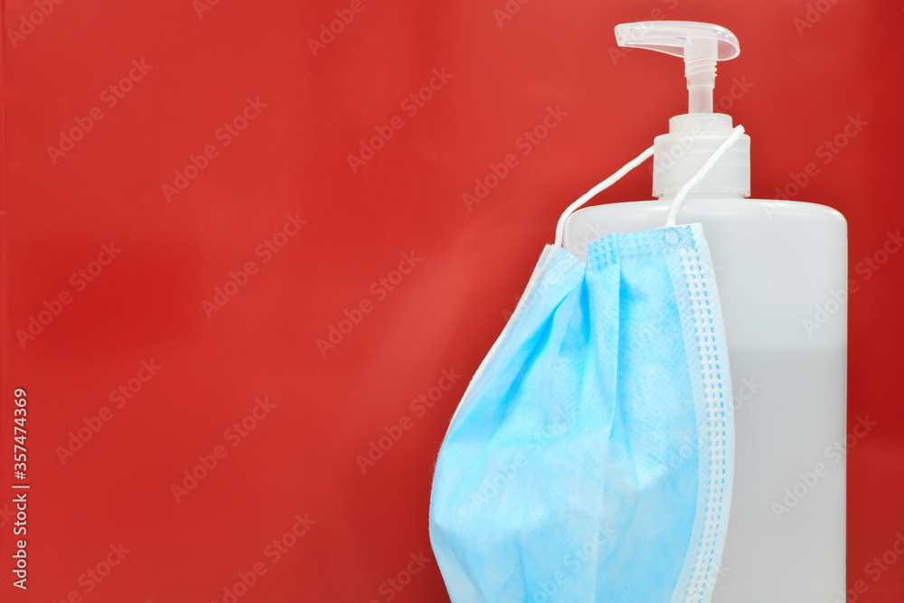 White hand sanitizer or soap dispenser and a blue face mask in red ...