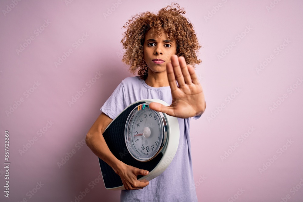 African american slim woman with curly hair holding scale over isolated ...