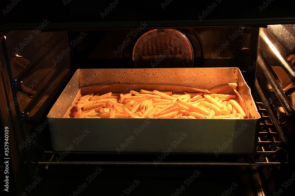 Homemade french fries in a roasting pan baked in the oven Stock Photo ...