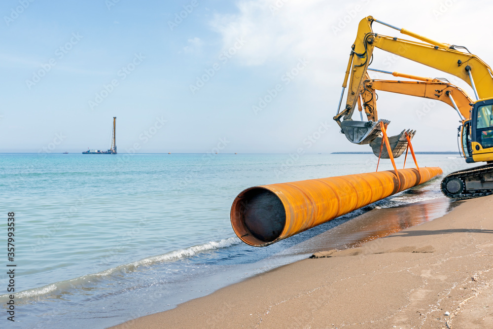 Excavators are carrying pile pipe to sea. Pipe piles are either a ...