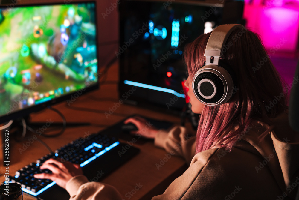 Image of caucasian focused girl playing video game on personal computer ...